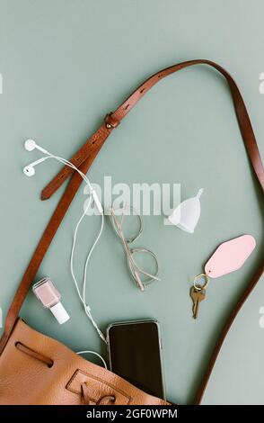 The vertical of the contents of woman's purse spilling against the gray ...