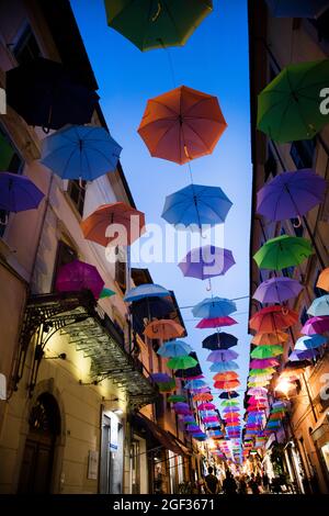 A series of umbrellas of different colors hanging along the main road ...