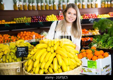 Young woman choosing bananas at grocery store Stock Photo - Alamy