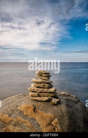 A meditative rock cairn on top of a boulder with long exposure ocean ...