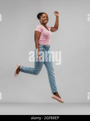 happy african american woman jumping over grey Stock Photo - Alamy