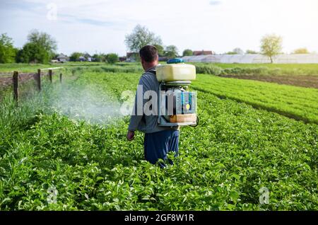 Farmer sprays pesticides on plantation. Use of chemicals for protection ...