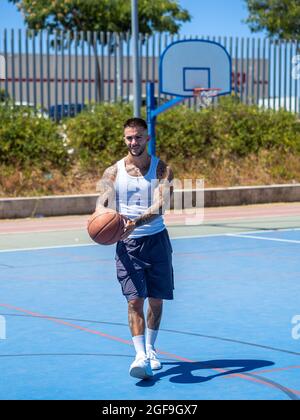 Athletic handsome Spanish basketball player training on a basketball ...
