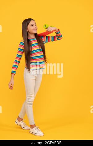 Teen hipster girl skater with skateboard water bottle and headphones on ...