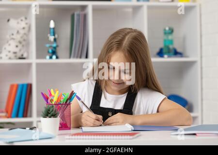 happy kid write in workbook at school lesson in classroom wear uniform ...