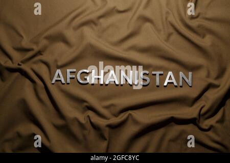 the word taliban laid with silver metal letters on rough tan khaki ...