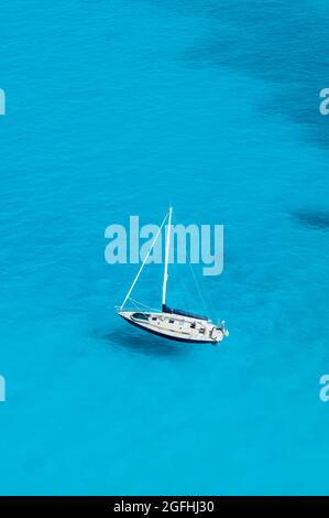 An aerial view of a sailboat cruising on a calm sea near an island ...