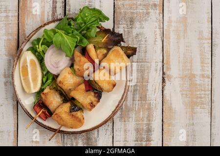 Skewed sole fish served with salad on a wooden table Stock Photo - Alamy