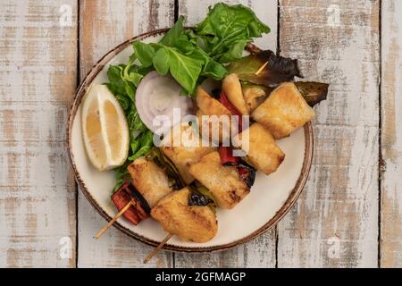 Skewed sole fish served with salad on a wooden table Stock Photo - Alamy