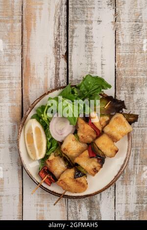 Skewed sole fish served with salad on a wooden table Stock Photo - Alamy
