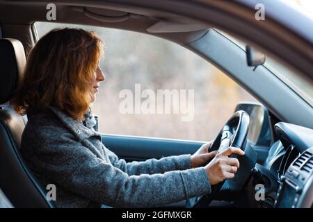 Young redhead woman driver driving a car smiling happily Stock Photo ...