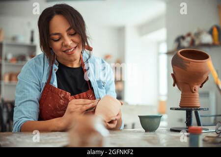 Cheerful female potter sanding ceramics in pottery workshop Stock Photo ...