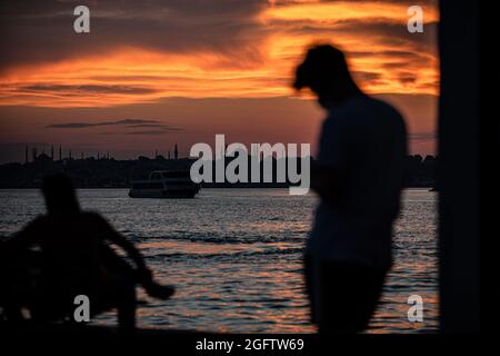 Silhouettes of people on the beach of Kadikoy watching the sunset ...