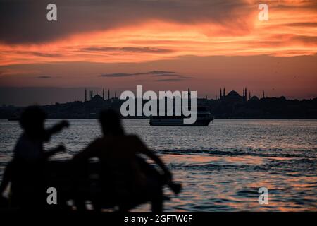Silhouettes of people on the beach of Kadikoy watching the sunset ...