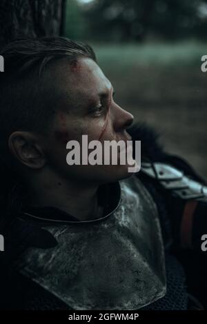 Medieval tired warrior knight in chain mail armour sits and rests among ...