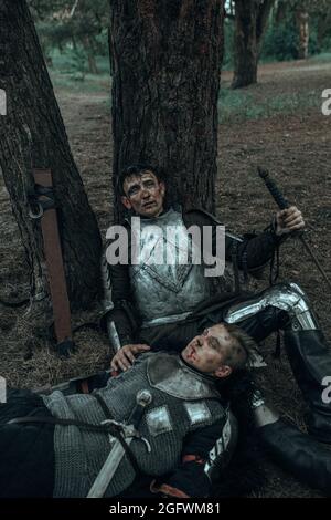 Two tired medieval warriors knights in chain mail armour rest among ...
