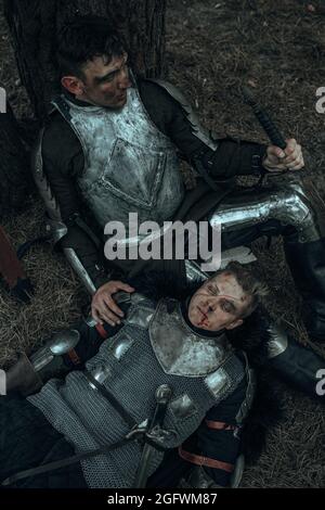 Two tired medieval warriors knights in chain mail armour rest among ...