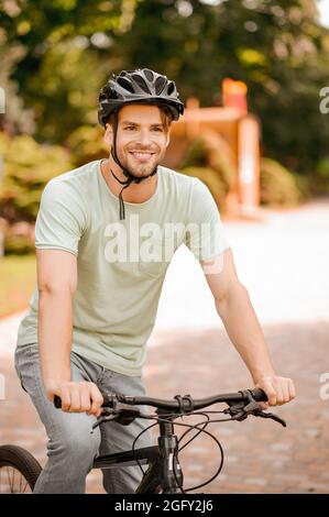 handsome sportive male bicyclist riding bike and observing environment ...