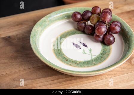piece of grapes in a ceramic design plate Stock Photo - Alamy