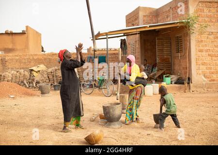 A family works together to grind flour for their next meal using a ...