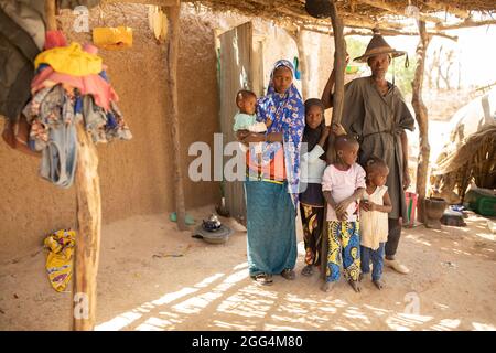 A family of traditional Fulani cattle herders stand together outside ...
