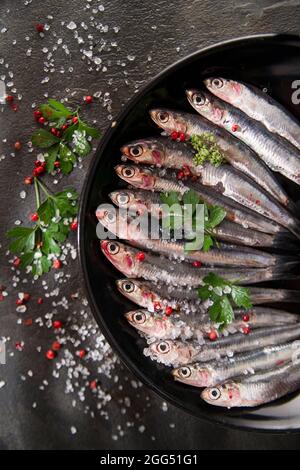 Presentation of a dish of raw anchovies on black background Stock Photo ...