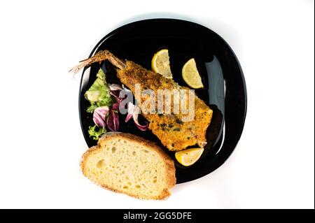 black plate with breaded monkfish on white background Stock Photo - Alamy