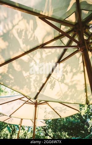 Sunlight through white parasol umbellar. Garden furniture function ...