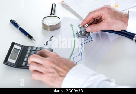 Businessman holding a stethoscope on a graph showing growth, geometric ...