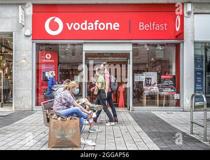 Shoppers sit outside Vodafone Store on Royal Avenue in Belfast. (Photo ...