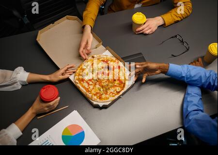 Team of managers eats pizza, business lunch in IT office. Professional ...