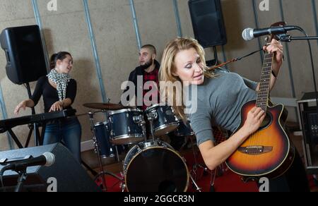 Lovely guitar player and singer with band Stock Photo - Alamy