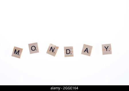 WORD MONDAY. Wooden scrabble letters spelling the word MONDAY on white ...