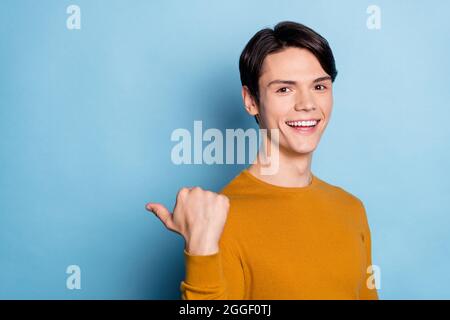 Photo of handsome guy indicate thumb finger empty space hold telephone ...
