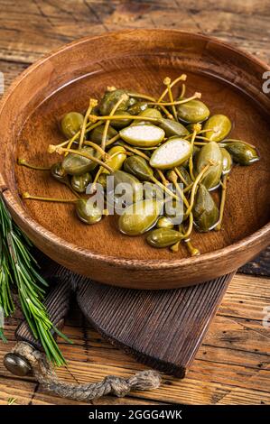Salted capers in vinegar in a wooden plate. wooden background. Top view ...