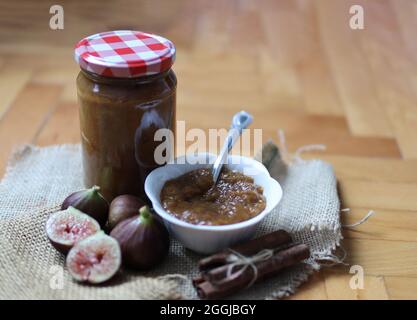 Wooden retro spoon in a jar full of plum jam on a desk. Close up ...