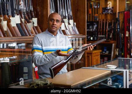 Hispanic salesman showing collectible rifled musket in gun store Stock ...