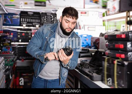 Positive male is standing with new impact wrench in tools store Stock ...