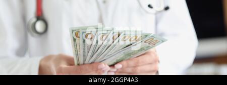 Doctor holding lot of dollar bills in his hands in clinic closeup Stock ...