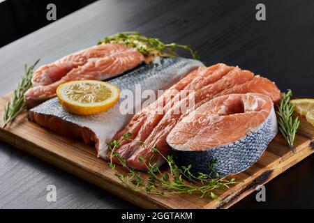 Raw salmon fillets and medallions with lemon and herbs on a wooden ...
