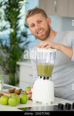 young man making mango smoothie and a blender on table Stock Photo - Alamy