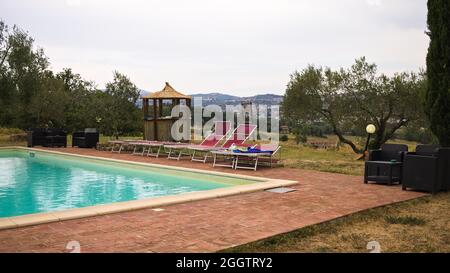 Red sunbeds by the pool in the Italian countryside (Umbria, Italy ...
