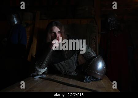 A mighty hero with long hair in chain mail armor in an ancient hall ...