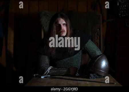 A mighty hero with long hair in chain mail armor in an ancient hall ...