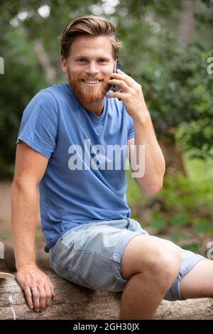 man sits on tree trunk in forest using laptop computer Stock Photo - Alamy