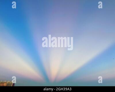 A rainbow and anti crepuscular rays at sunset over the rainforest near ...