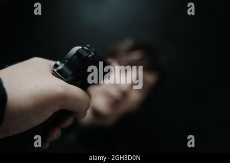 First person view of gun aimed at young man on dark background. POV of ...