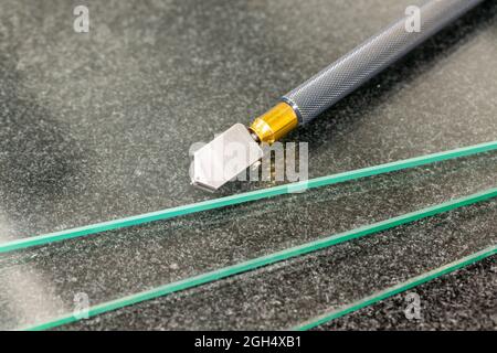The construction glass cutter is lying on a glass table. Tool on a ...