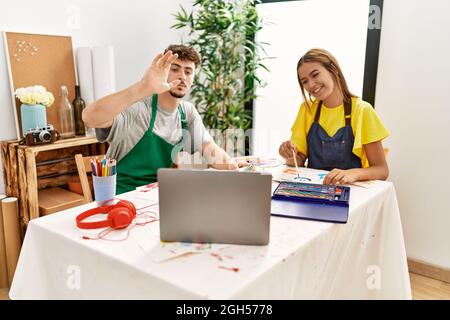 Young hispanic artist couple smiling happy showing painted palm hands ...