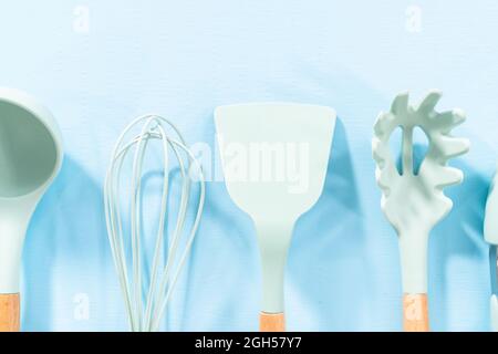 New blue silicone kitchen utensils with wooden handles on a pink ...